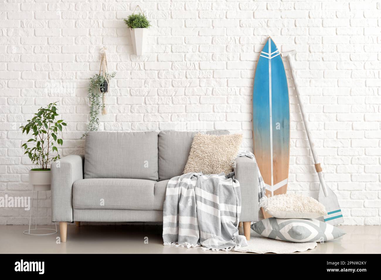 Interior of living room with surfboard, paddle and sofa Stock Photo - Alamy