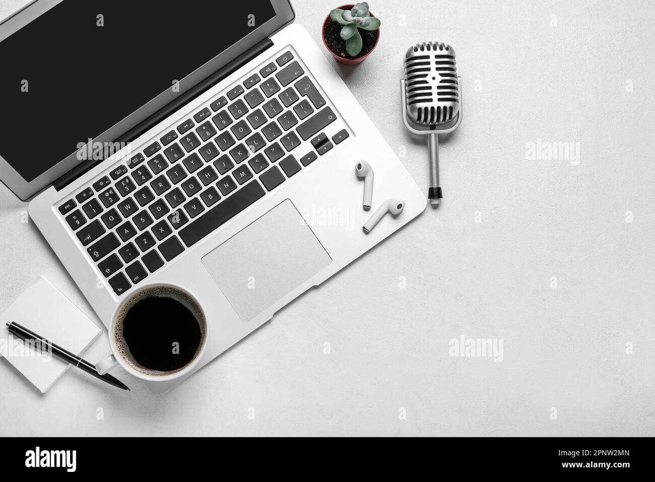 Laptop with earphones, microphone, sticky notes and cup of coffee on ...