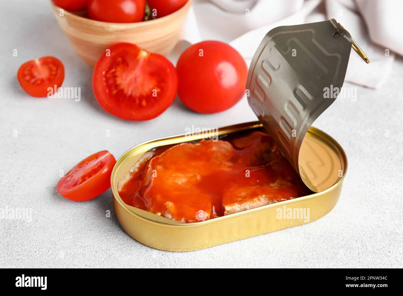 Opened can with fish in sauce and tomatoes on white table Stock Photo ...