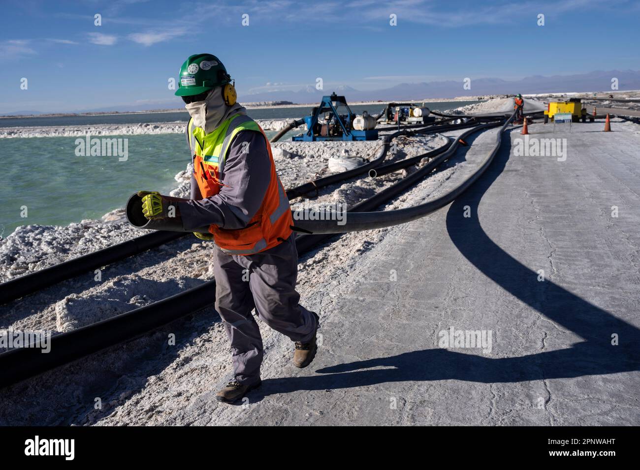 Workers perform maintenance next to pools of brine slowly turning into ...