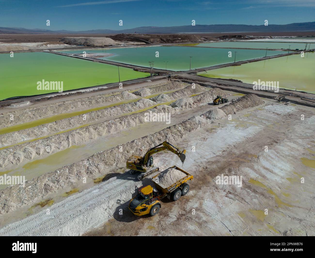 An excavator scoops lithium-packed salt into a dump truck at the SQM ...