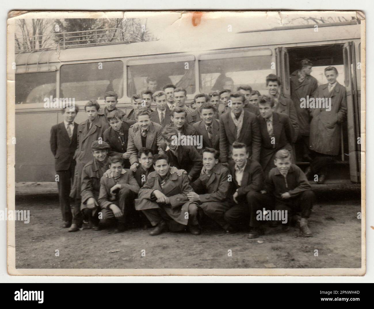 Vintage photo shows young students pose in front of bus. Photo has ...