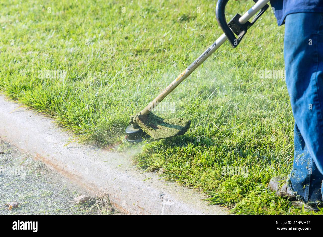 Municipal worker lawn mower mowing fresh green grass near road with his ...