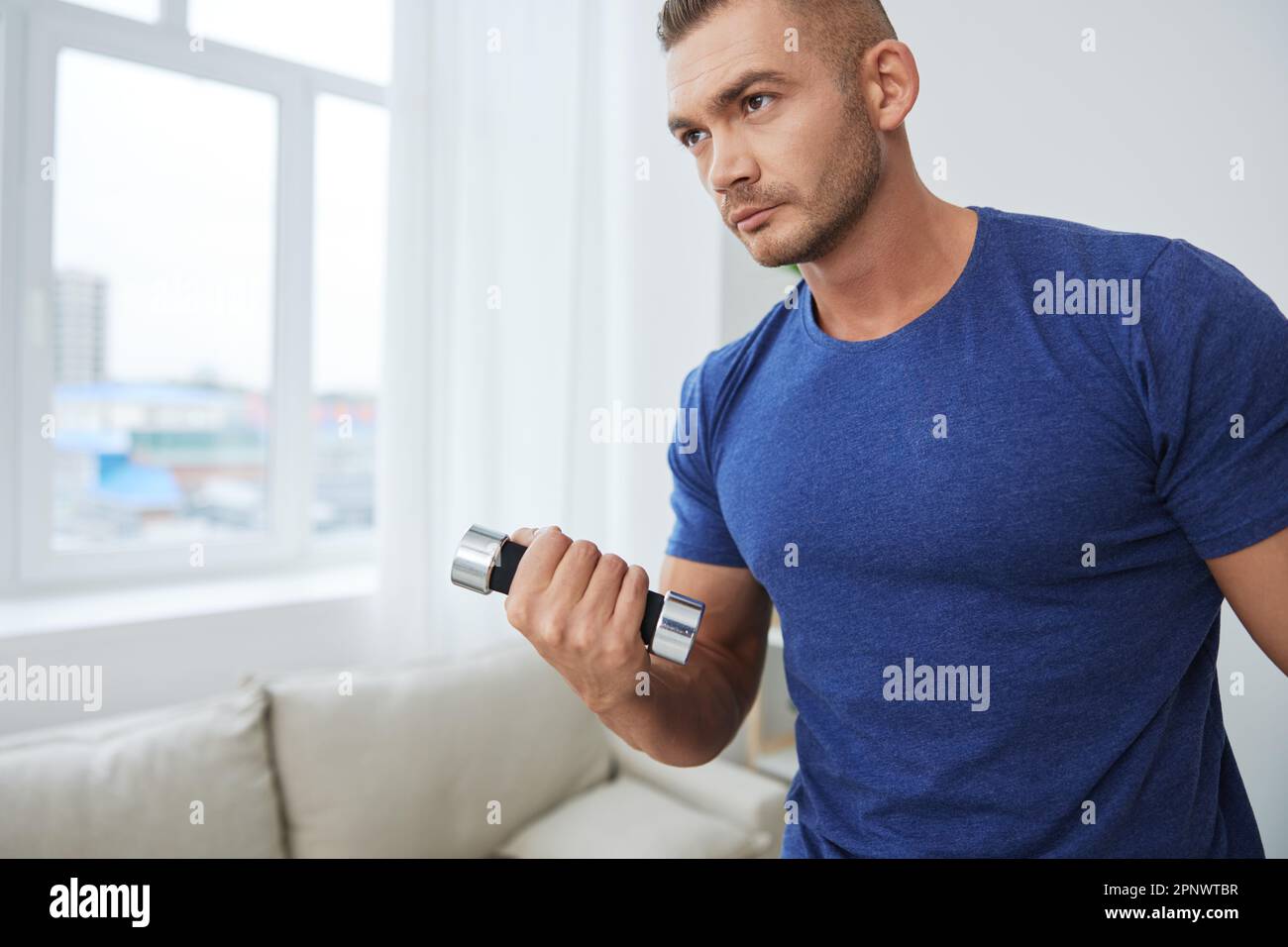 Man sportsman training at home with dumbbells, exercises for arms and ...