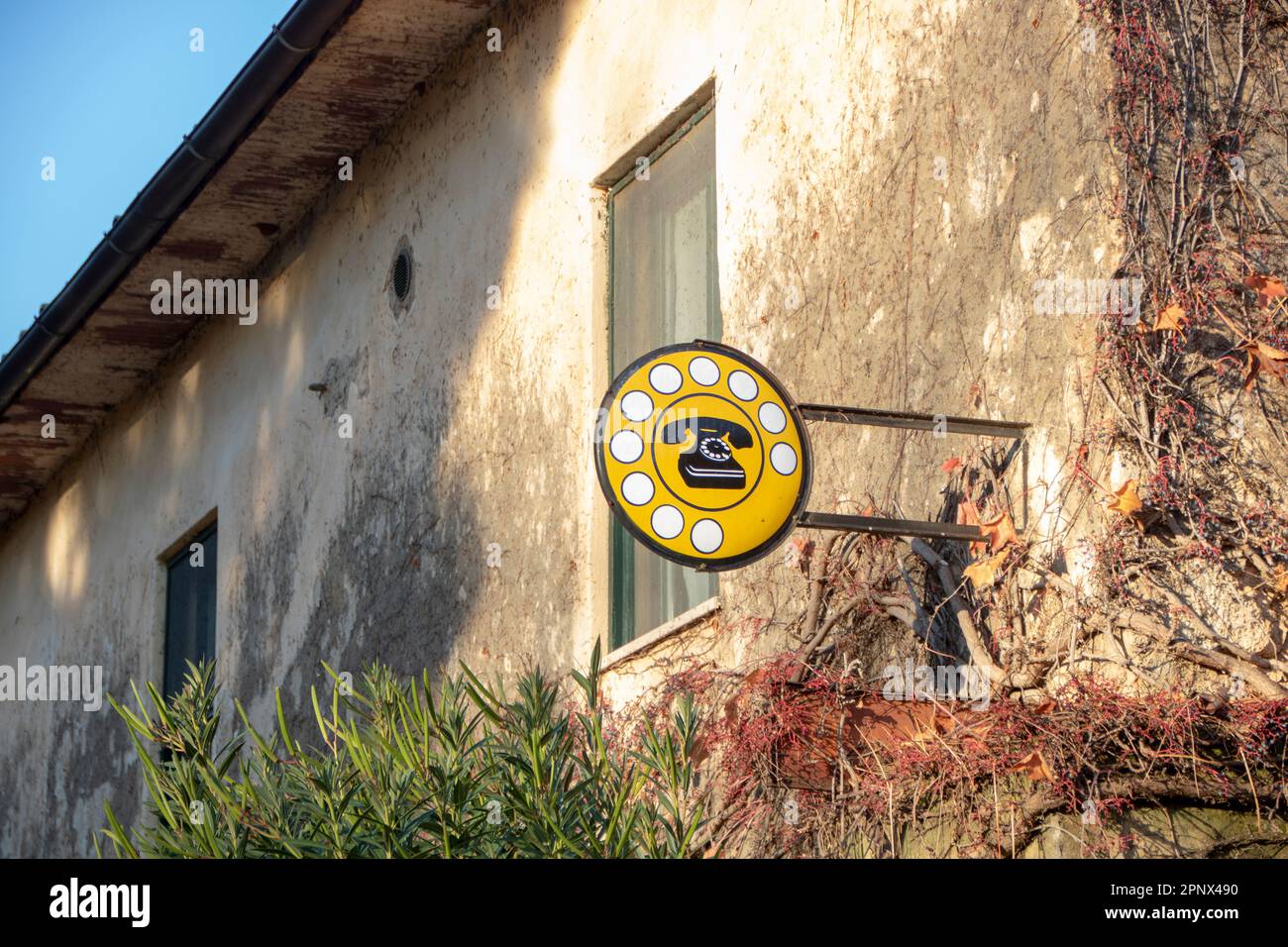 old public telephon sign hanging from a stone wall in Tuscany, Italy ...