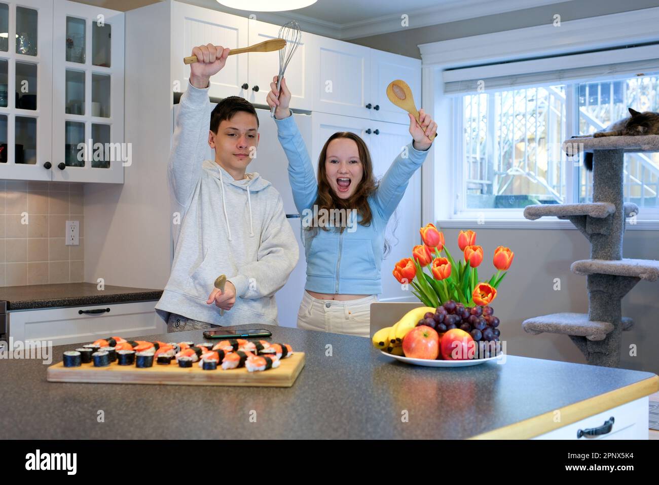 Overjoyed young Caucasian couple dancing singing preparing healthy food ...