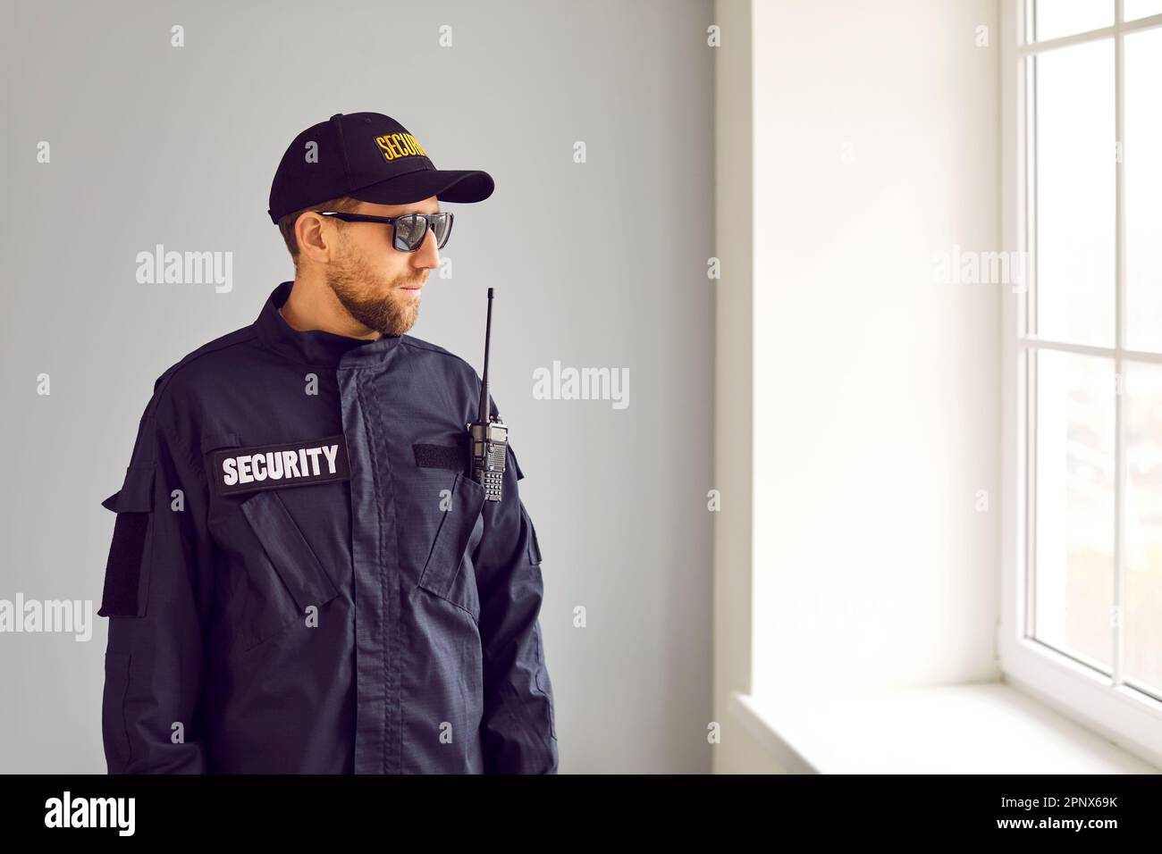 Security guard man in uniform and sunglasses standing inside house and ...