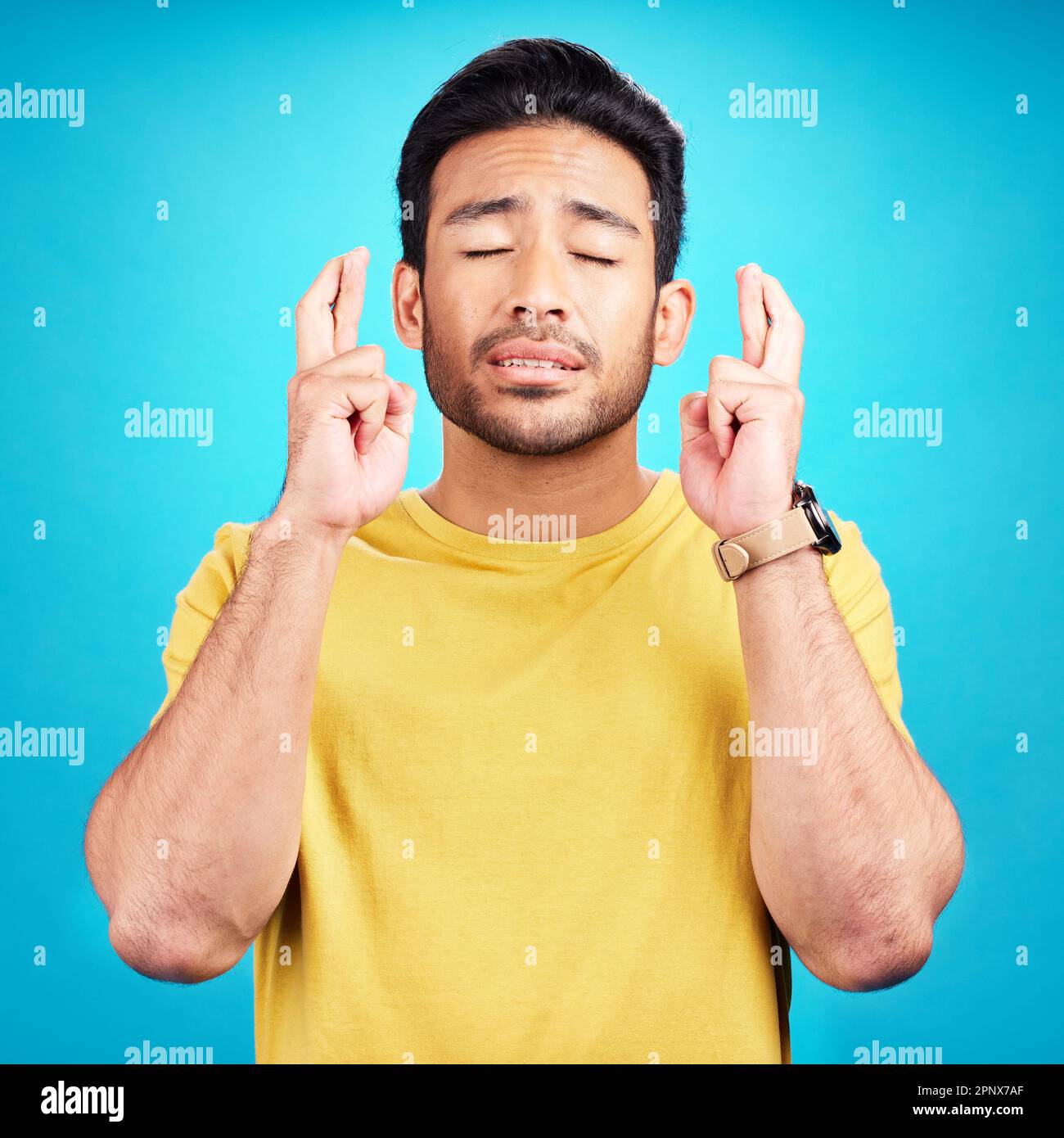 Hope, man and fingers crossed for luck in studio isolated on a blue ...