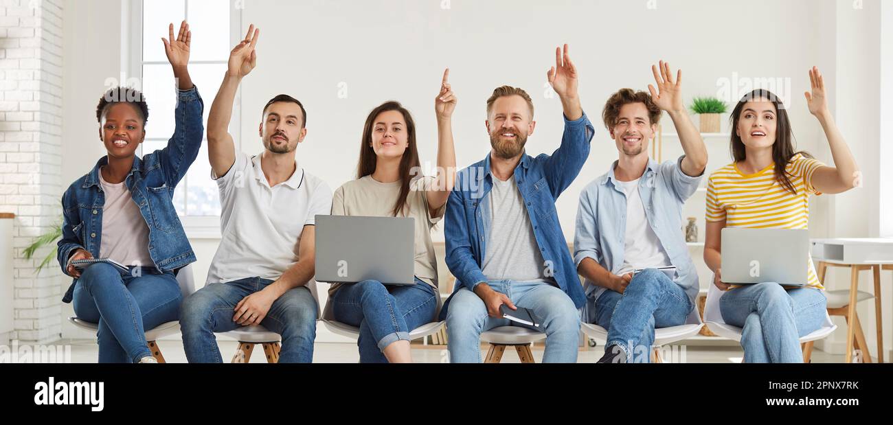 Group of satisfied multiracial listeners raise their hands to ask ... Group of satisfied multiracial listeners raise their hands to ask ...
