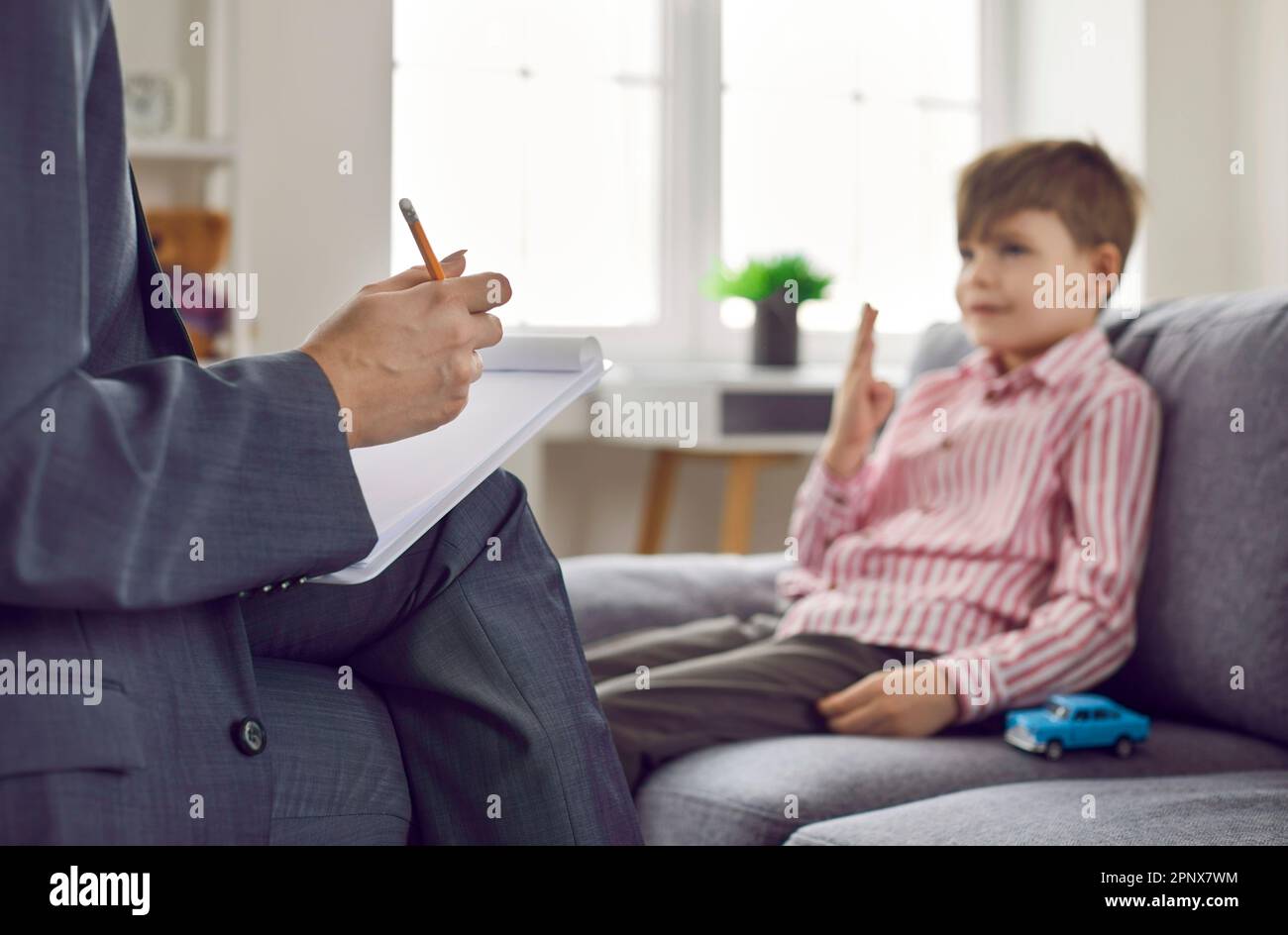 Psychologist or therapist with pencil and clipboard asking little child ...