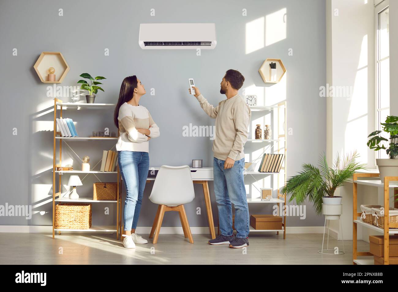 Young family couple setting up the temperature on the air conditioner ...