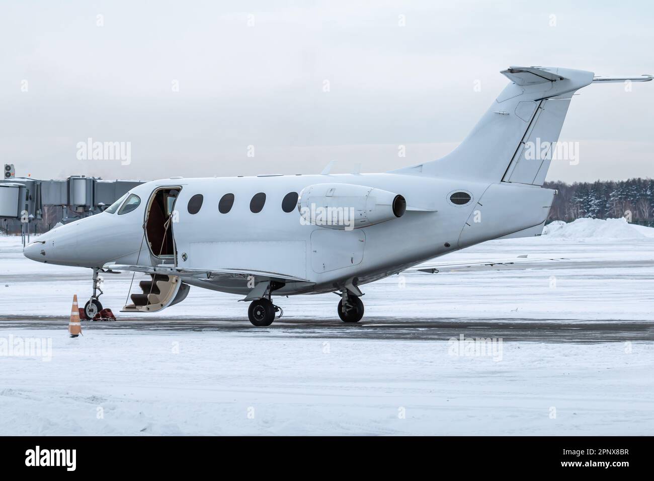 Modern white business jet with an opened gangway door at the winter ...