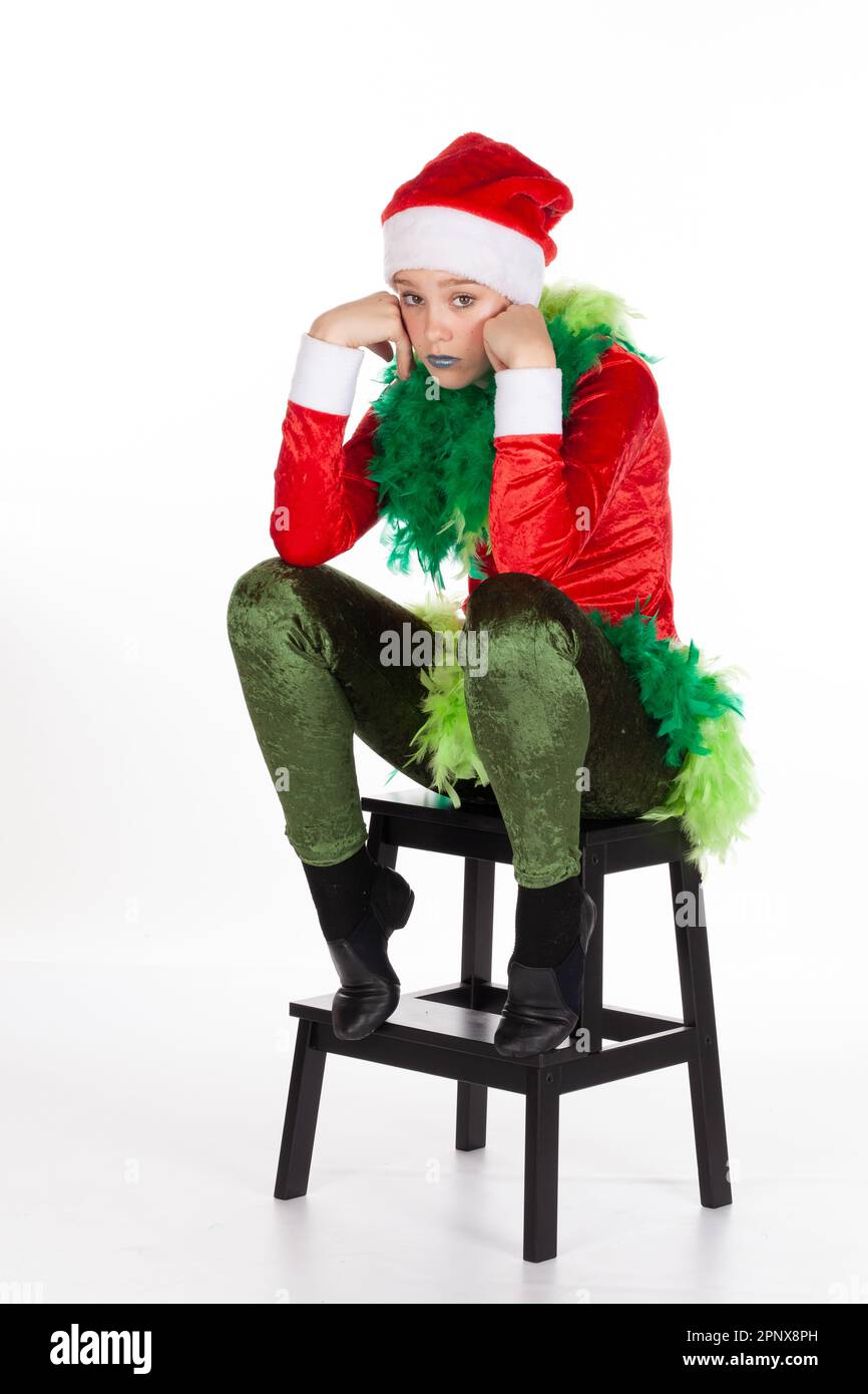 Sitting young girl wearing red santa clause hat like a grinch hands to ...