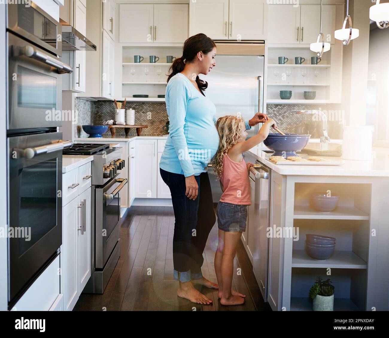 Baking has become a family hobby. a little girl helping her mother bake ...