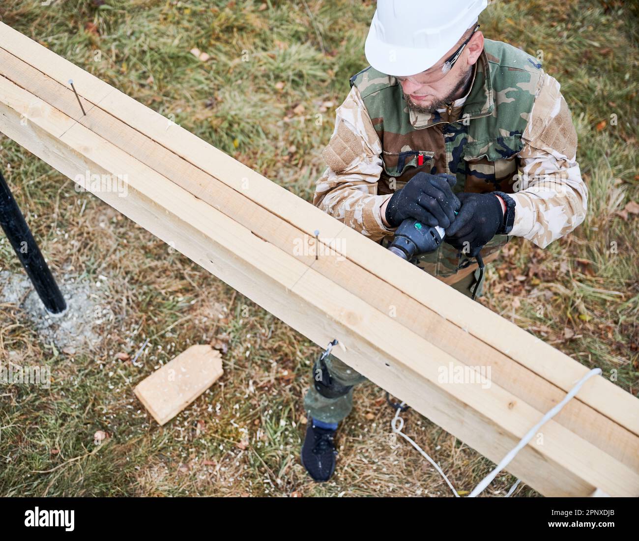 Man building wooden frame house on pile foundation. Male worker ...