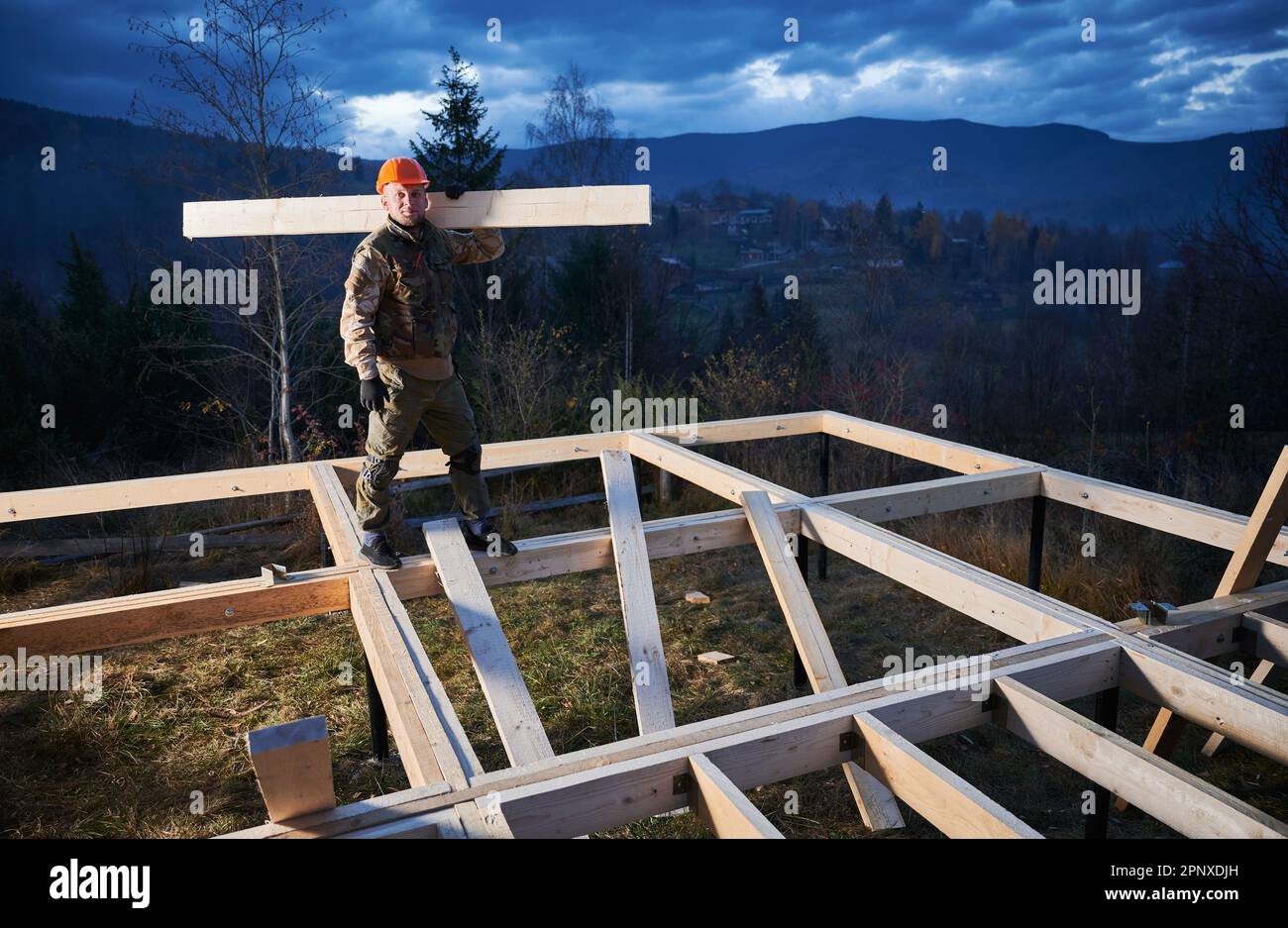 Man worker building wooden frame house on pile foundation. Carpenter ...