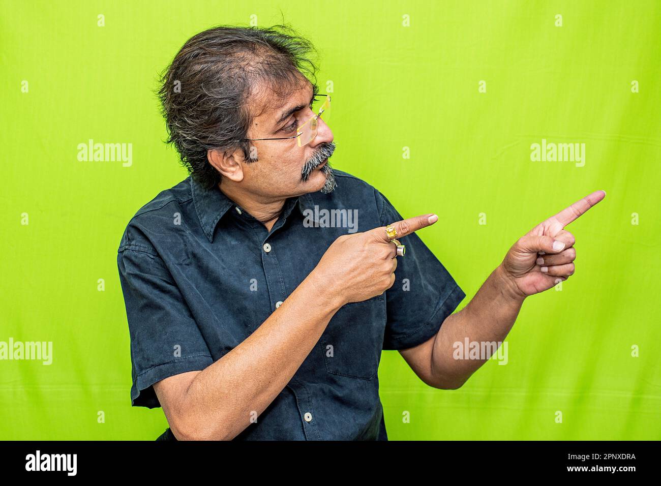 A smart corporate businessman in black shirt pointing top-right with ...
