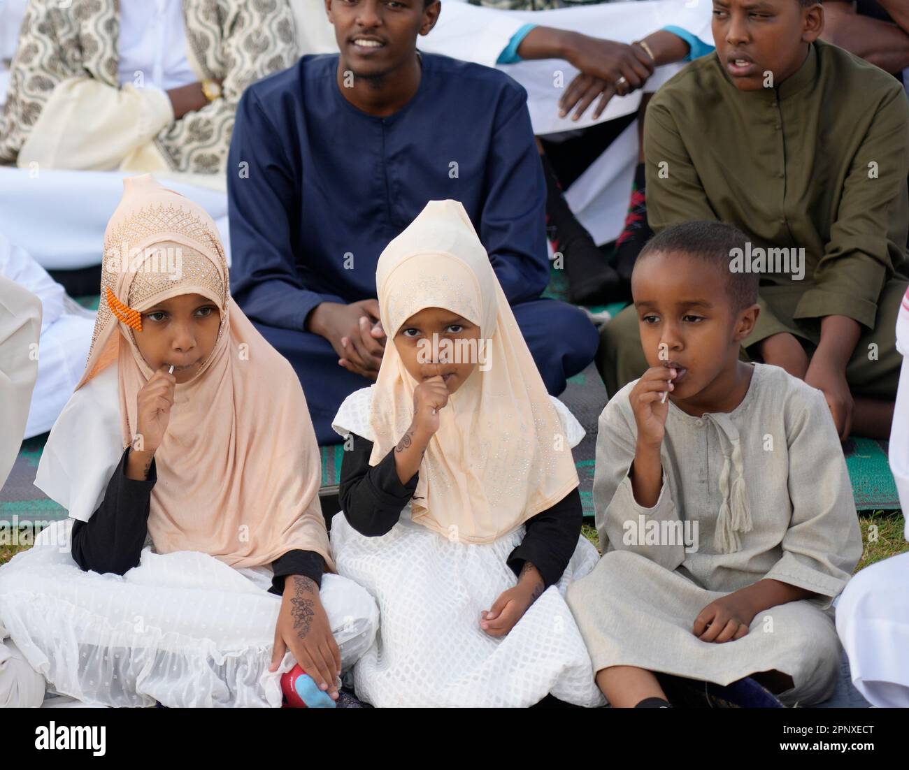 Kenyan Muslims children chew lolly pop as they wait to pray in an open ...