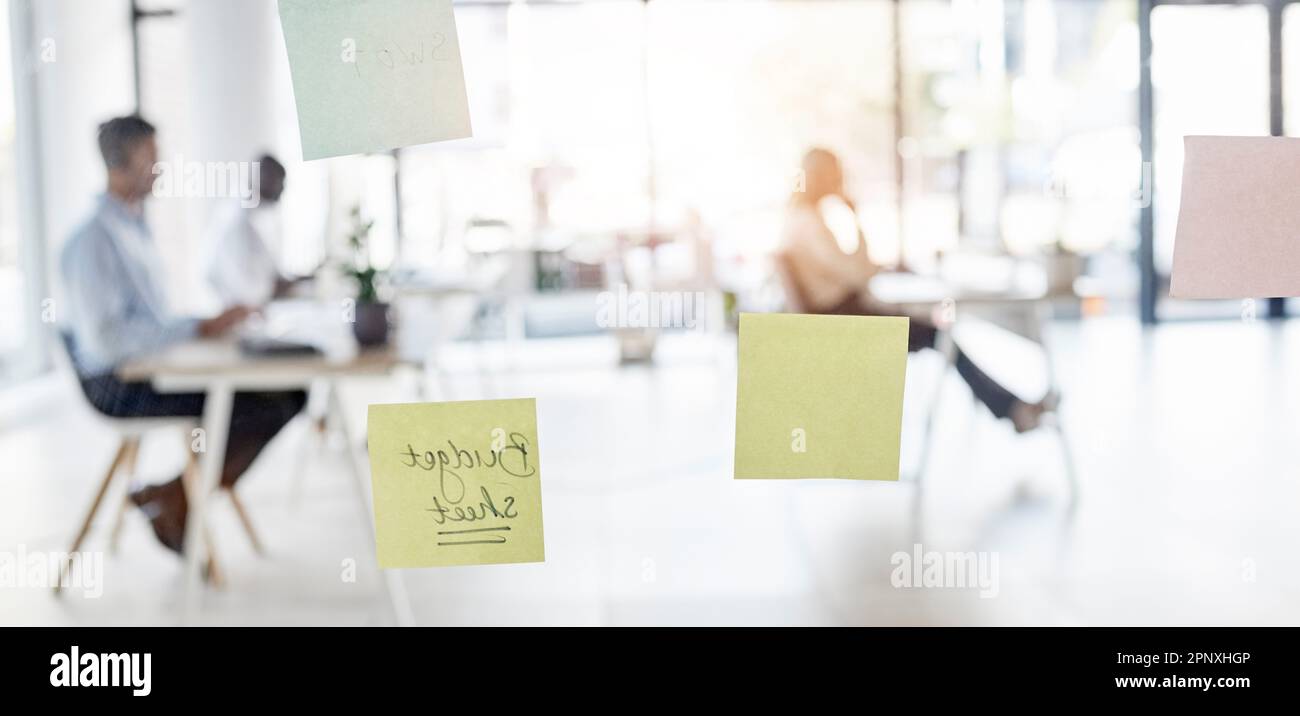 Sticky note, blurred background and business people sitting in an ...