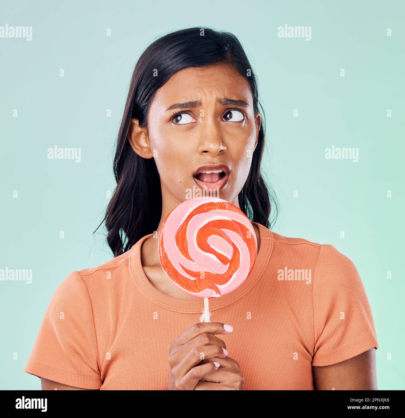 Thinking, lollipop and woman with candy in studio isolated on a green ...