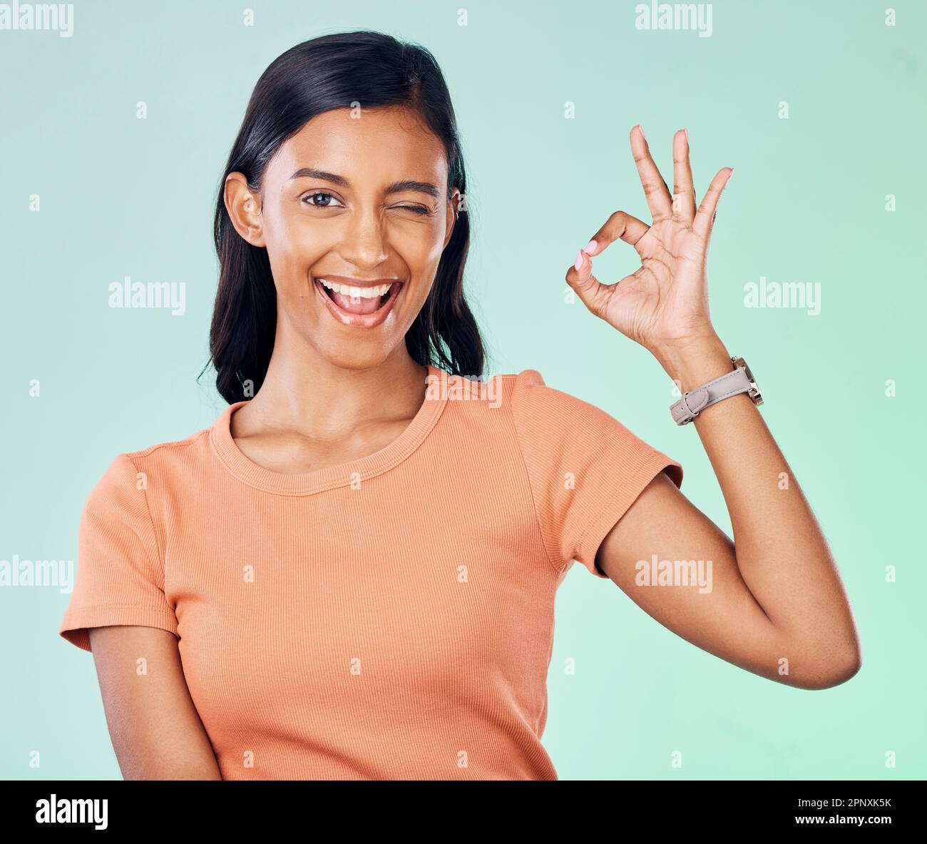 Portrait, wink and female with a perfect gesture in studio with a ...