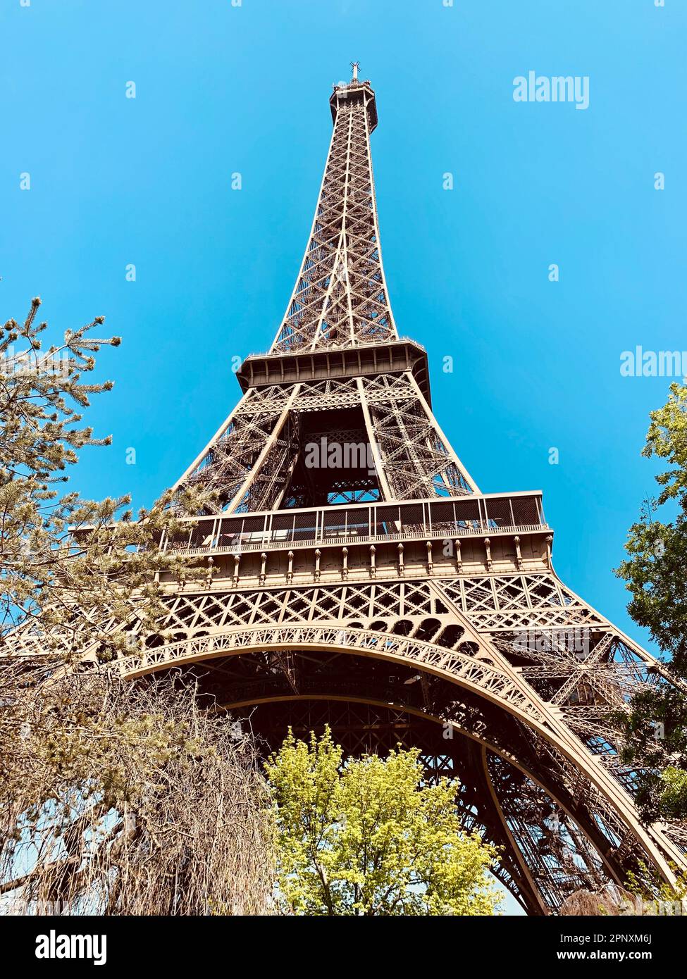 A low angle shot of the historic Eiffel Tower in Paris, France set against a vivid blue sky ...