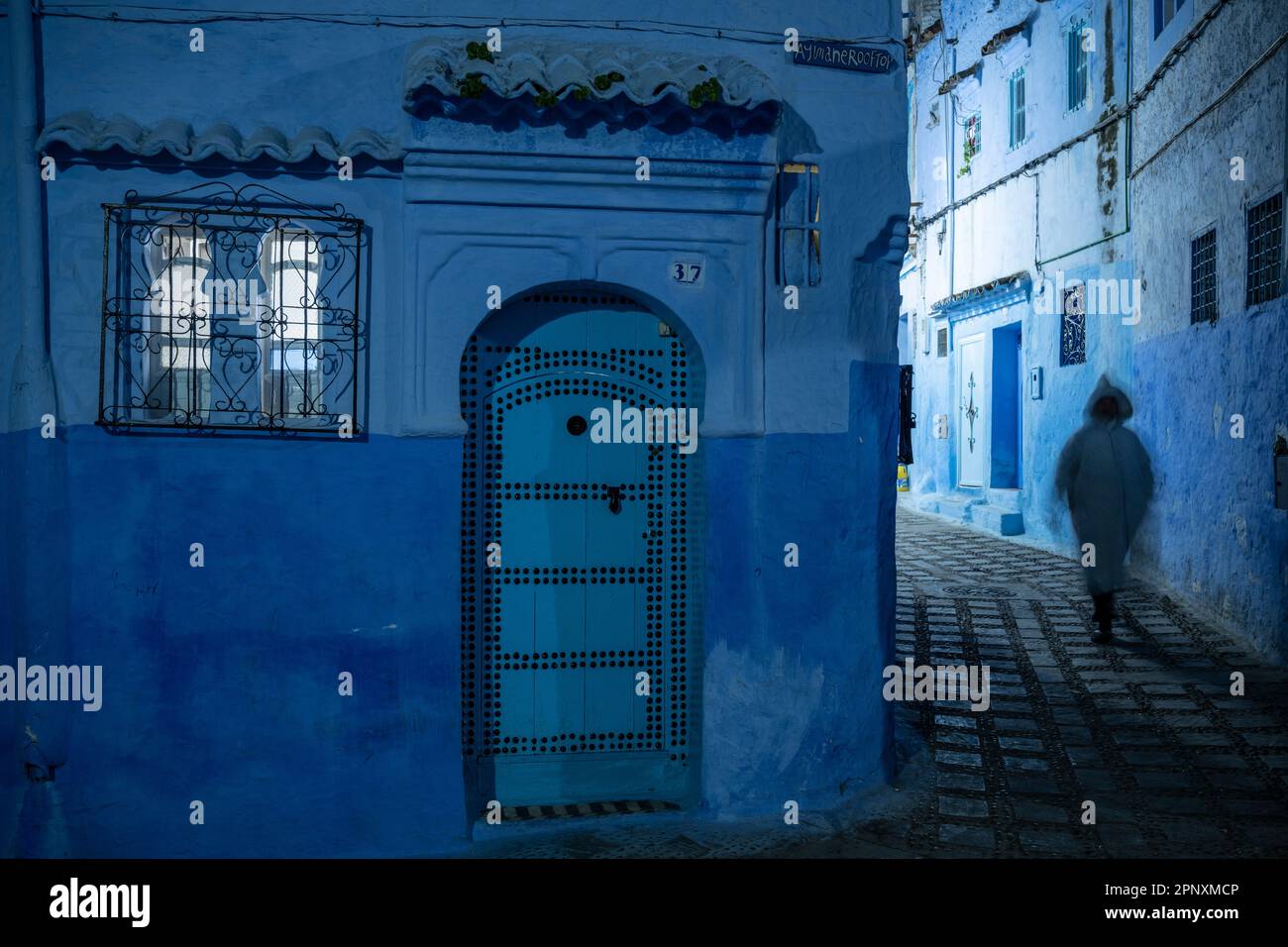 Silhouette of a man with djellaba walking through an alley in ...