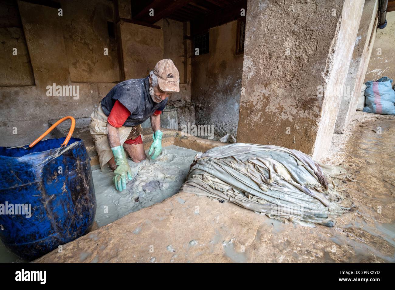Worker in the tanneries of Fez handling skins inside a pool, for ...