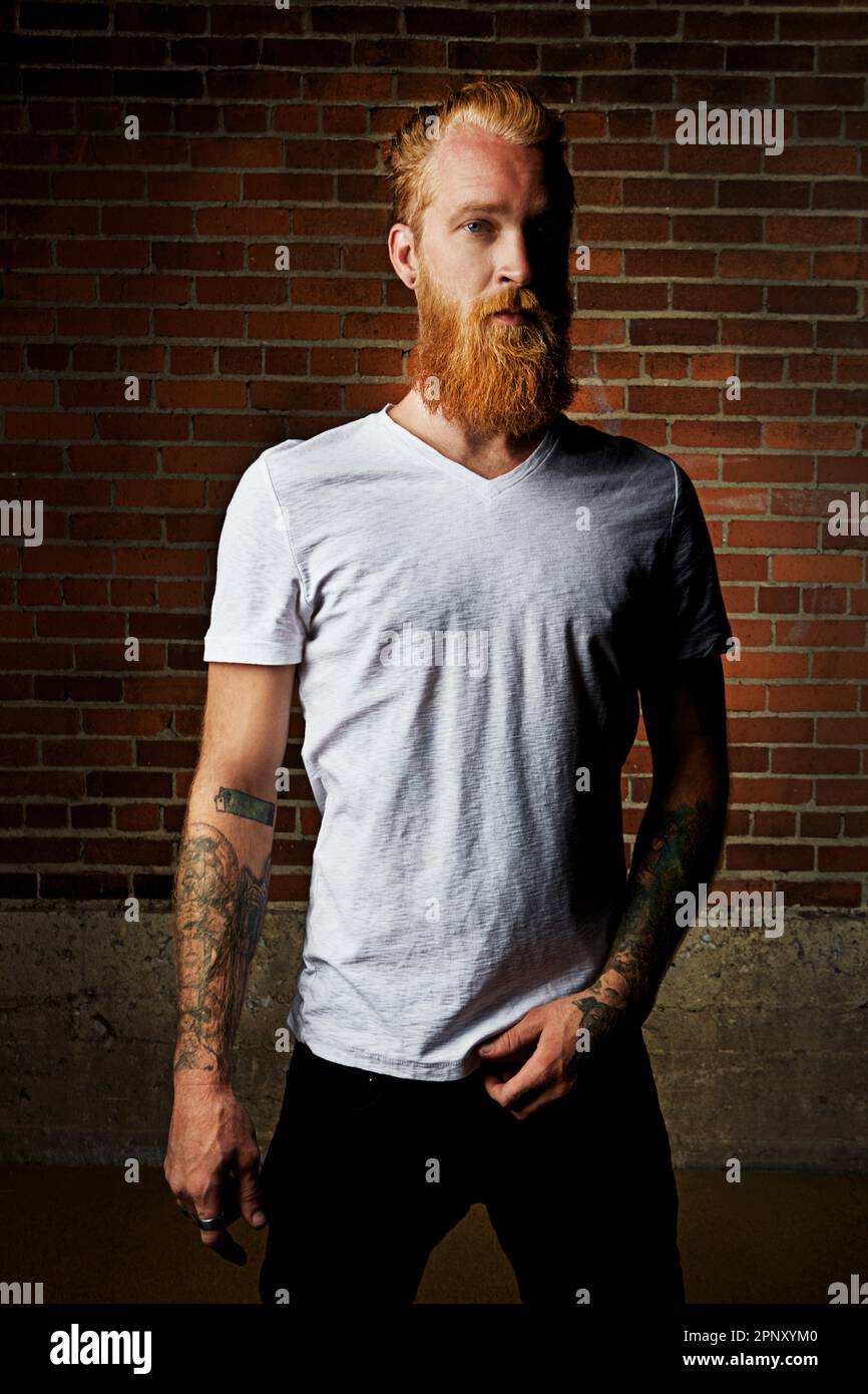 Long beards, the staple of a hipster. a handsome young man in trendy attire against a brick wall ...