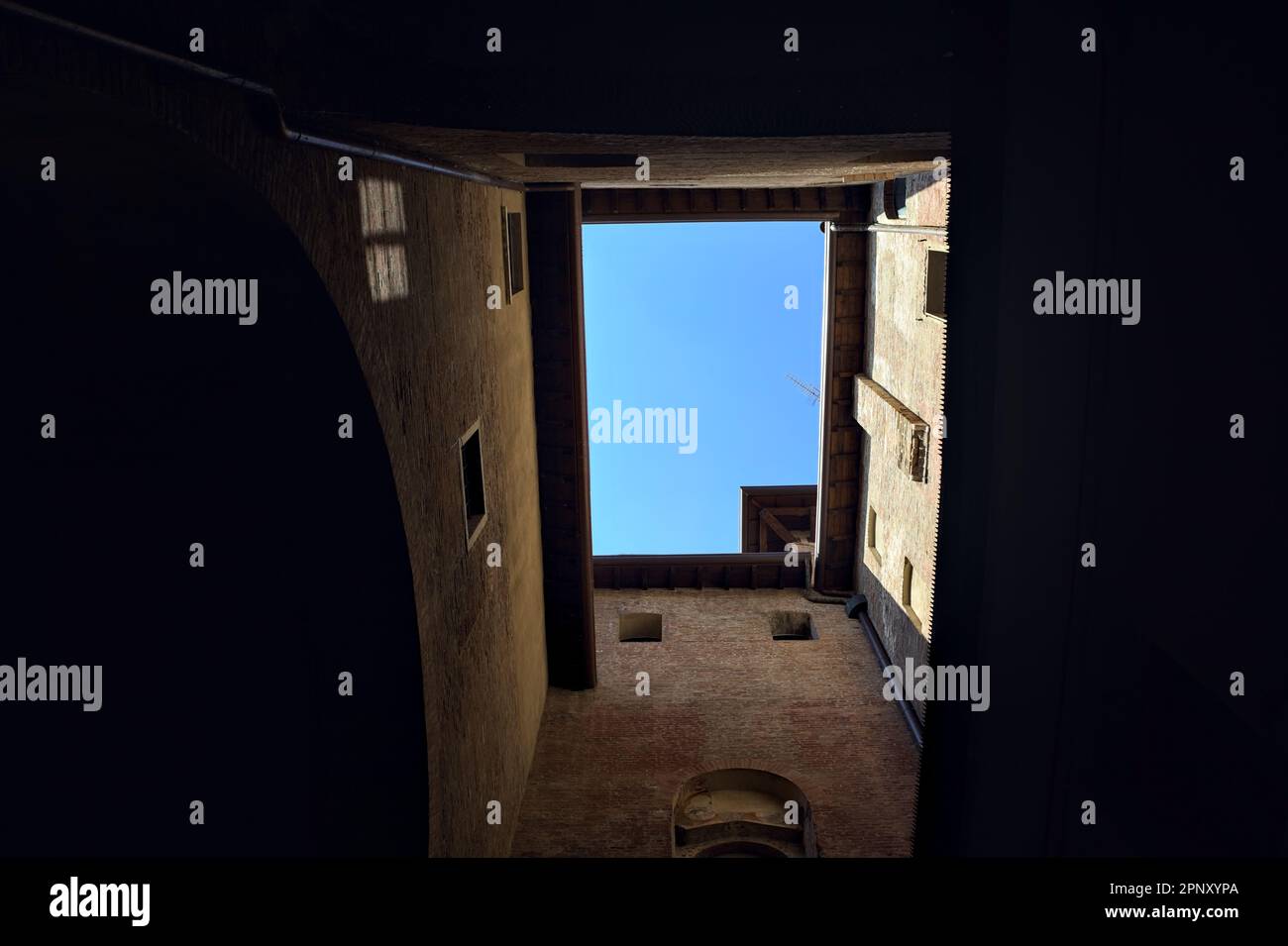 Opening between buildings in a covered alley with a clear sky above ...