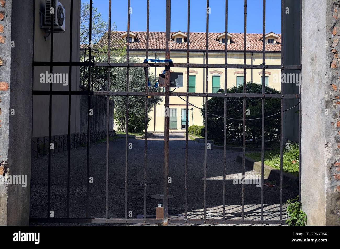 Locked gate and a building at the end of a path in a garden behind it ...
