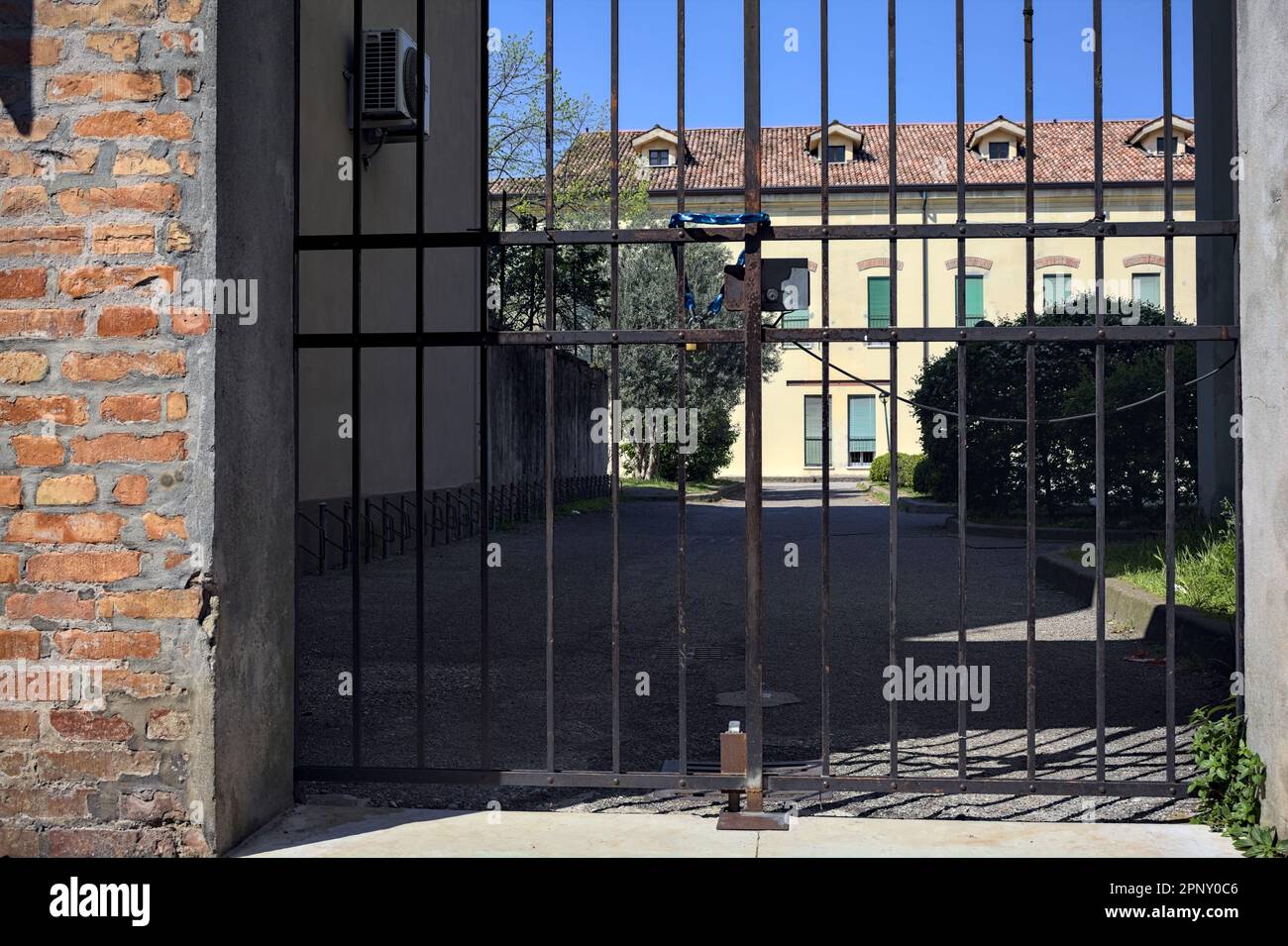 Locked gate and a building at the end of a path in a garden behind it ...