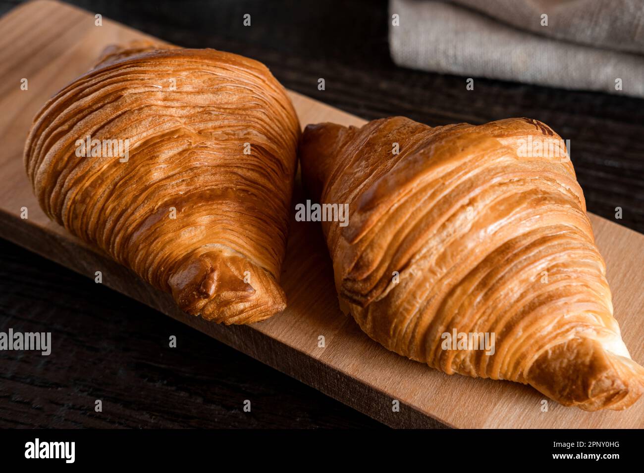 Two croissants on a wooden cutting board. Rustic dark table. Food ...