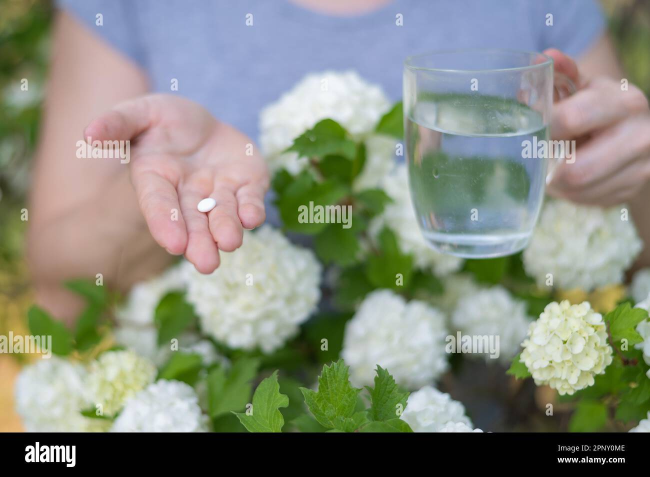 Woman holding an antihistamine tablet and a glass of water while in a ...