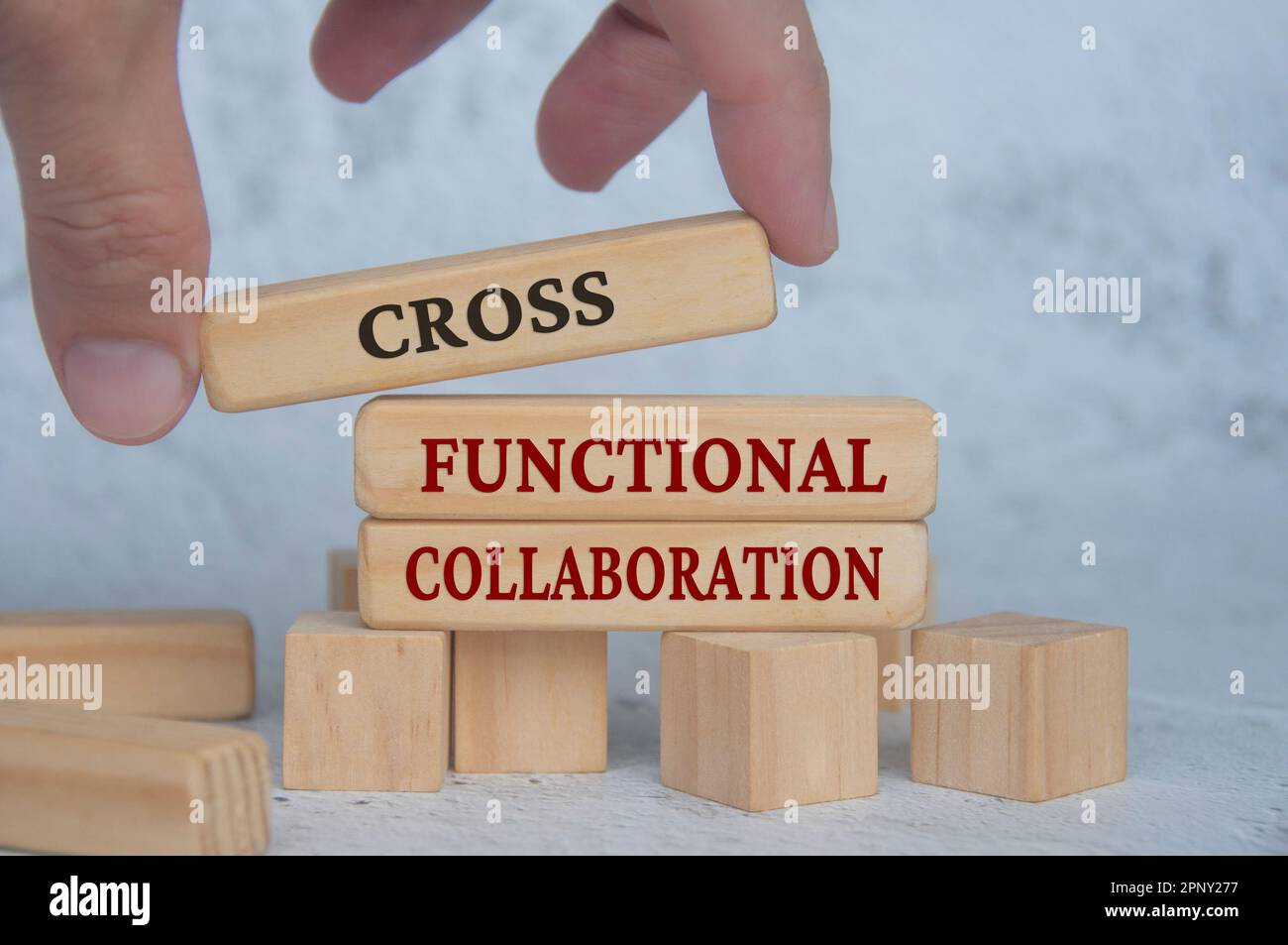 Hand Placing Wooden Blocks With Cross Functional Collaboration Text On
