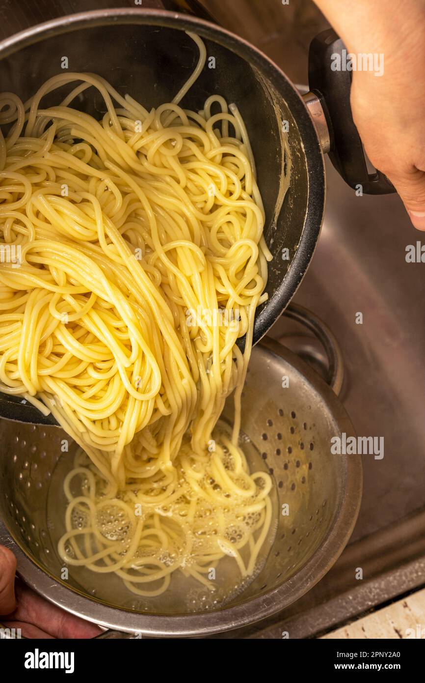 Spaghetti being poured into a colander. vertical photo Stock Photo - Alamy