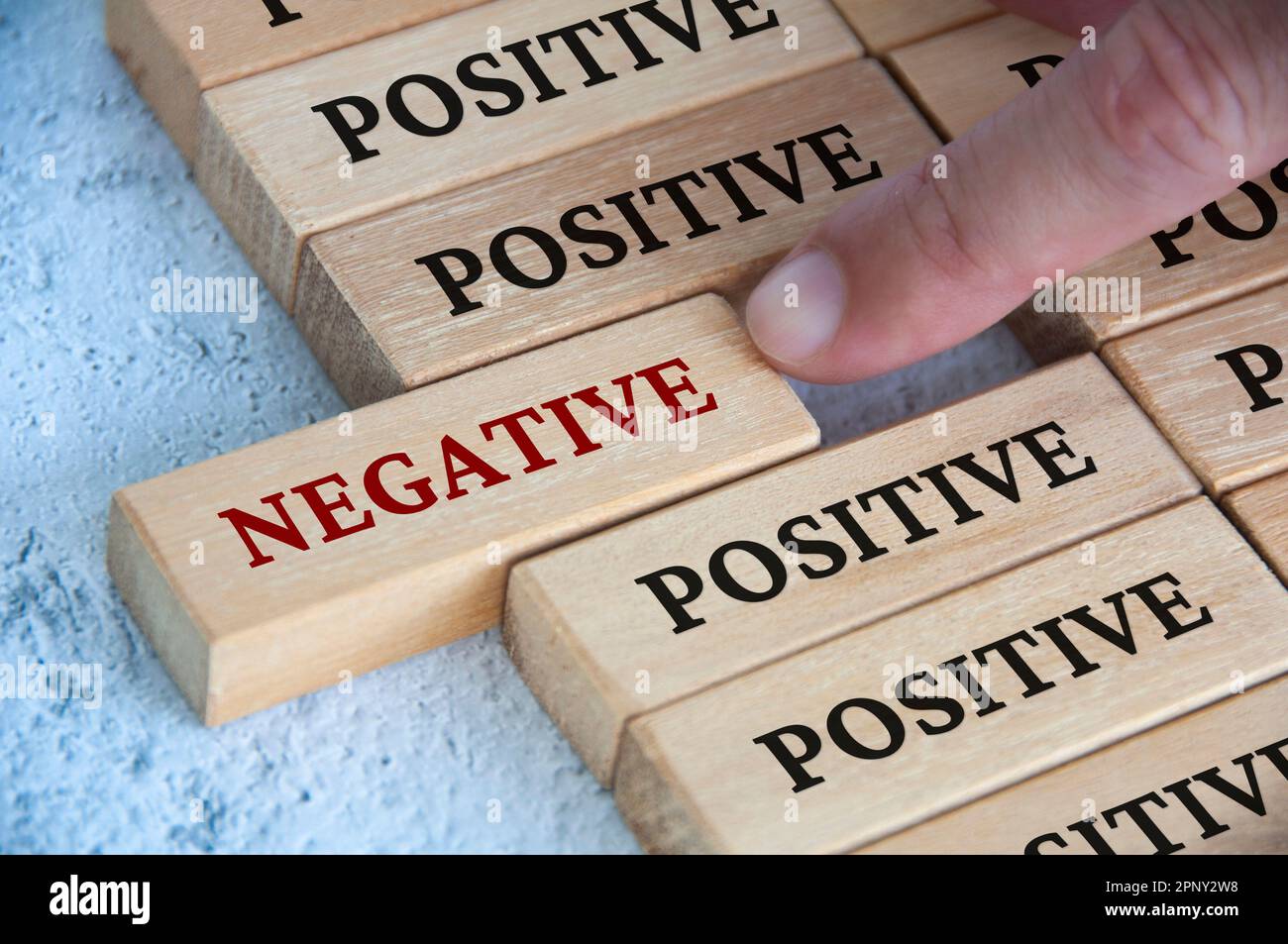 Finger pushing negative text on wooden block from the rest of the ...