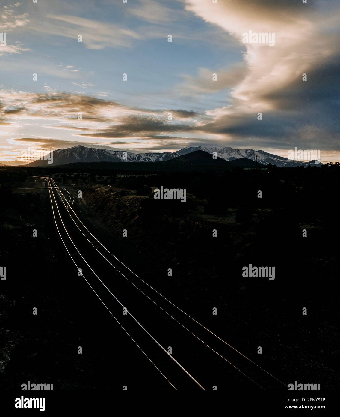 Railroad tracks recede into the distance with mountains at sunset Stock ...