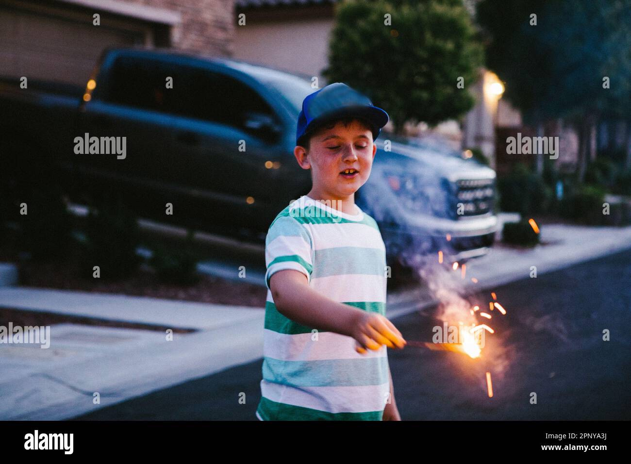 Boy holds a sparkler fire work on July 4th in the dark in neighborhood ...