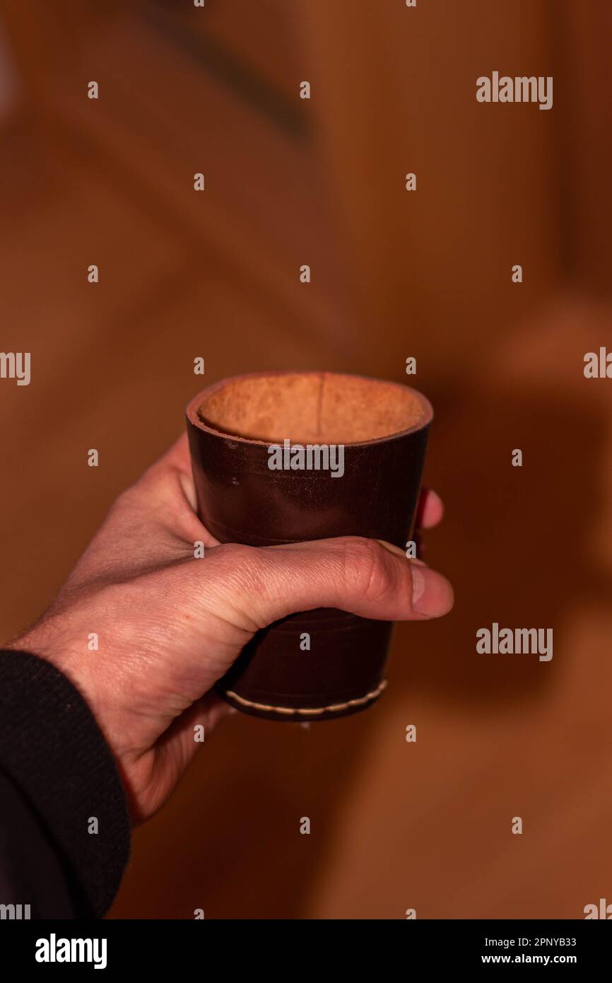 A close-up image of a hand grasping a brown, handle-less cup Stock ...