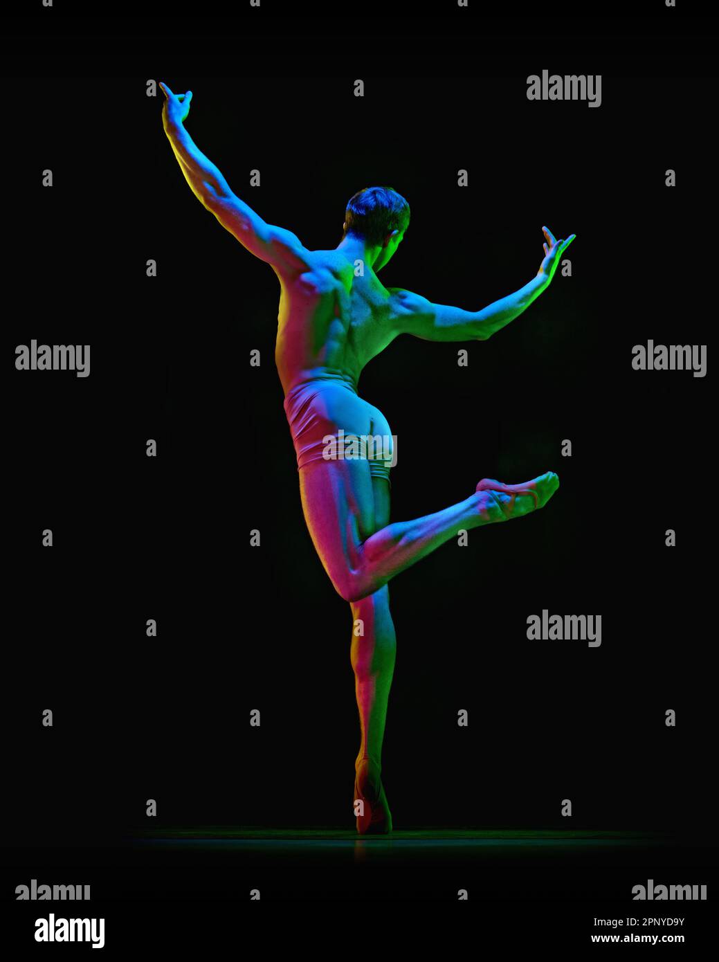 Portrait of graceful muscled male ballet dancer posing on one leg with ...