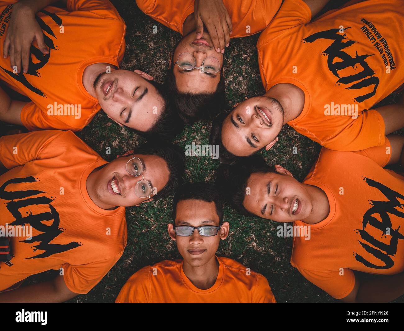 A top view of a group of diverse people wearing bright orange shirts ...