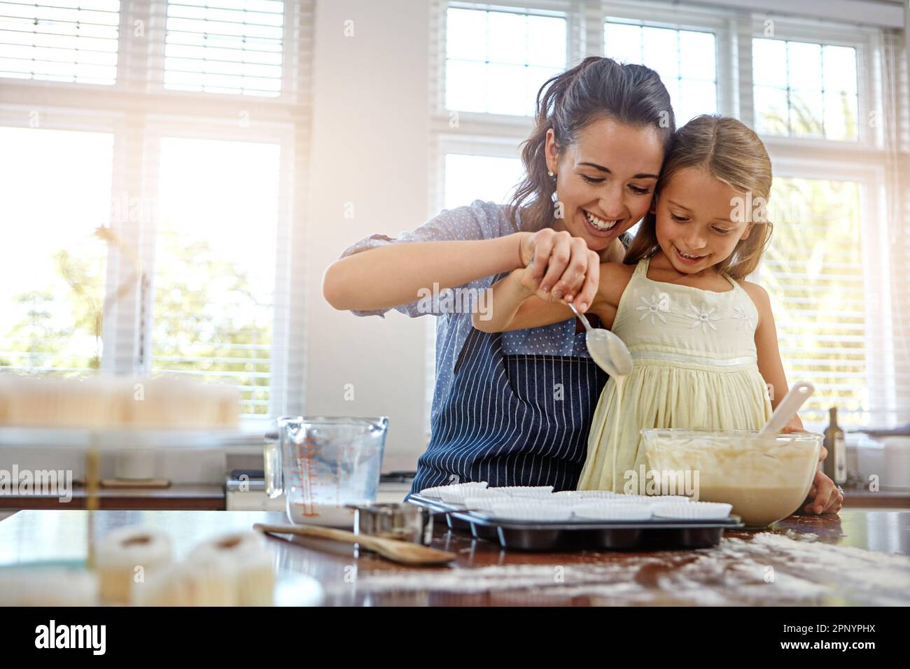 Baking with mom is fun. a mother and her daughter baking in the kitchen ...