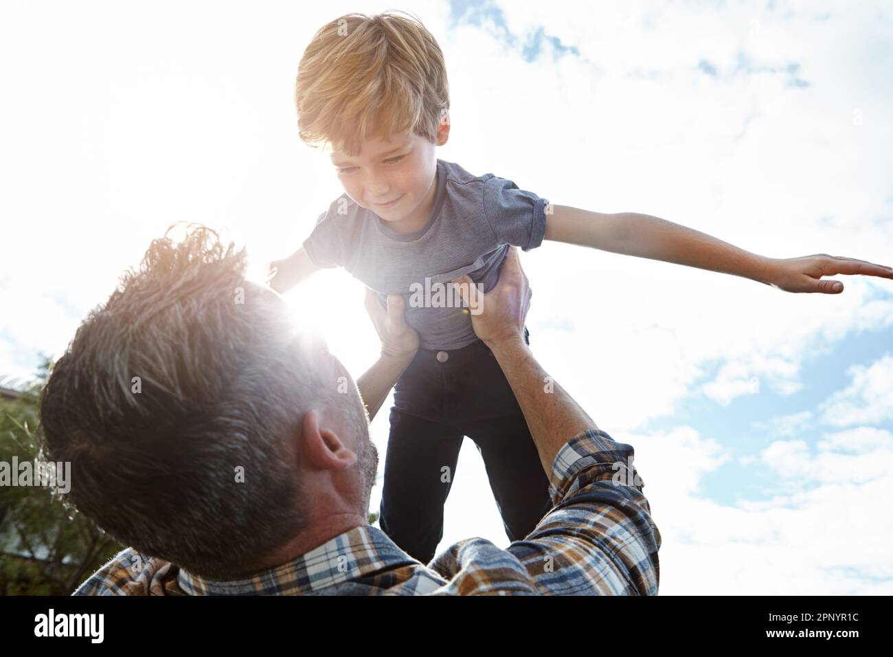Teaching his son to fly. a father lifting his son high into the air ...