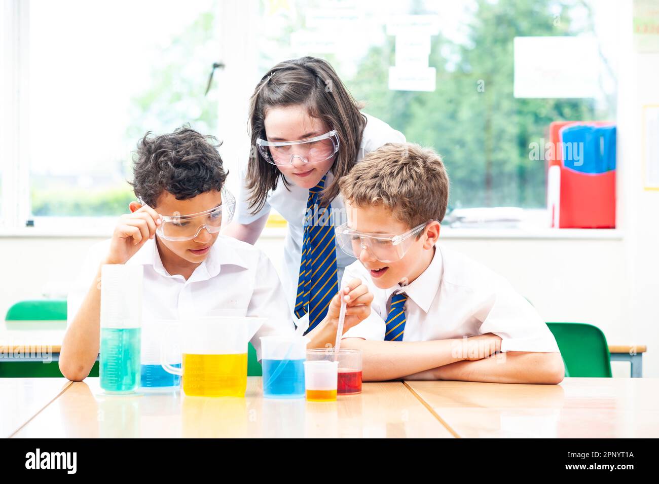 Three three young scientists in a science lab checking formulas and ...