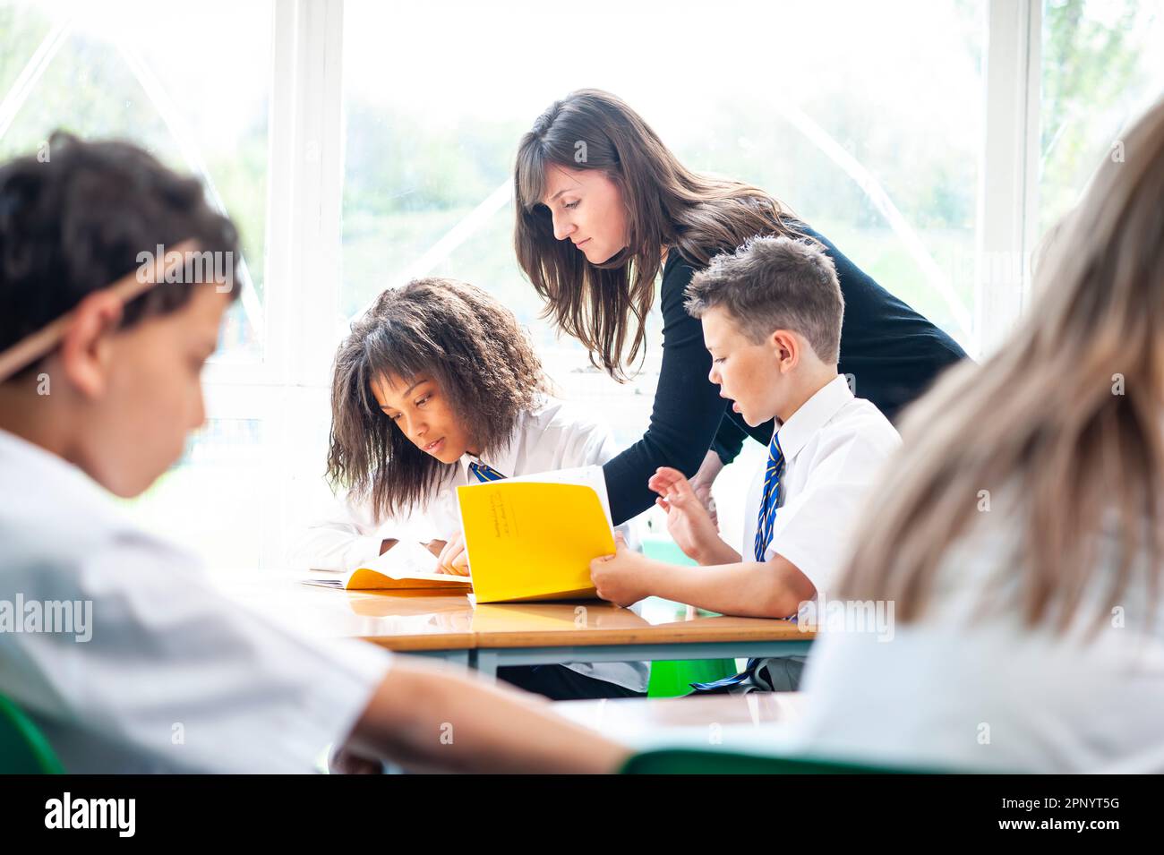 Teacher helping supporting checking peoples work Stock Photo - Alamy
