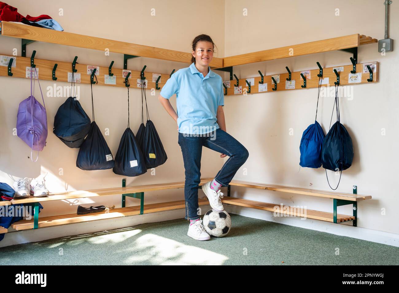 Young girl inspired by football with football in changing room / locker ...