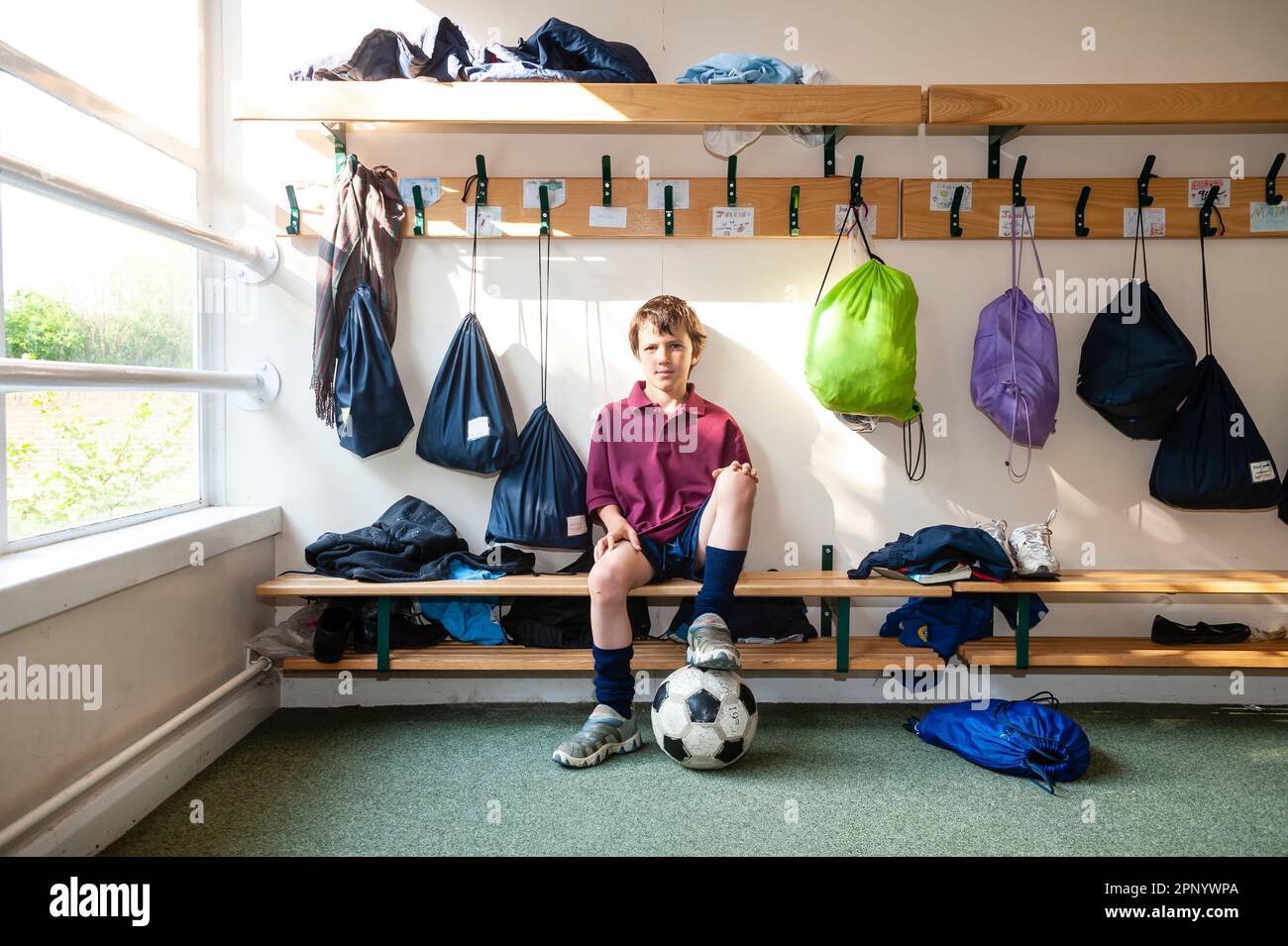 Young boy with his football in a changing room, locker room PE kit ...