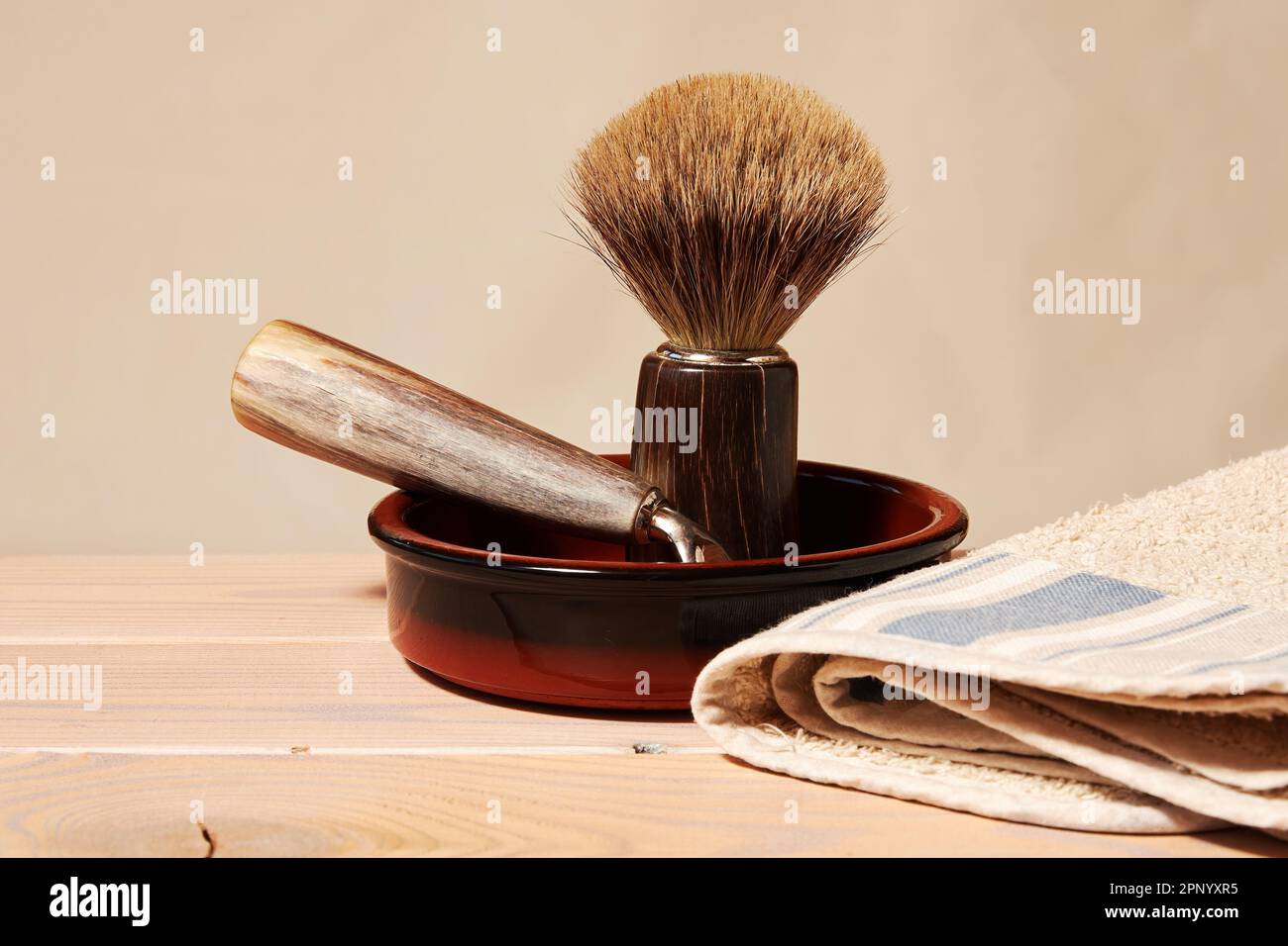 Bowl with shaving equipment, blade, brush and towel on the table in the ...