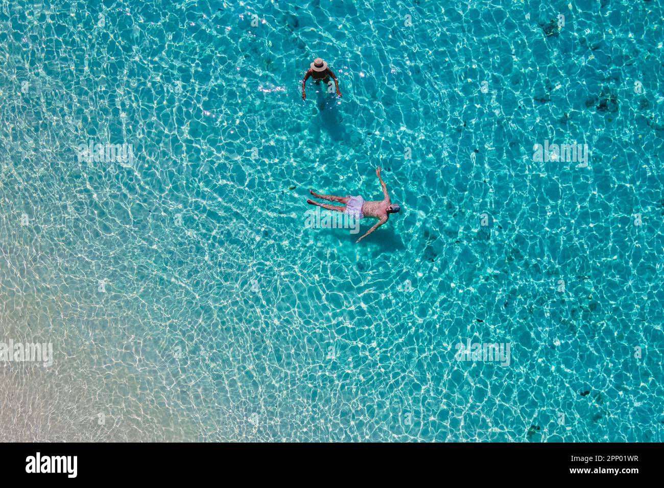 a couple swimming in the ocean of Koh Kradan Island with a white ...
